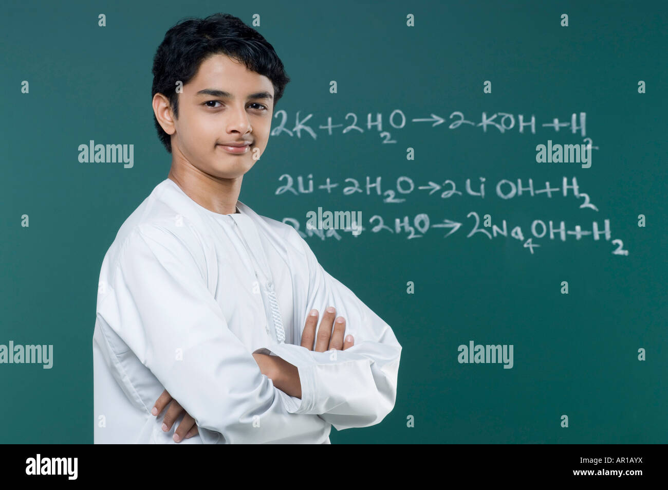 Teenage boy standing with folded hands by blackboard, portrait Stock ...
