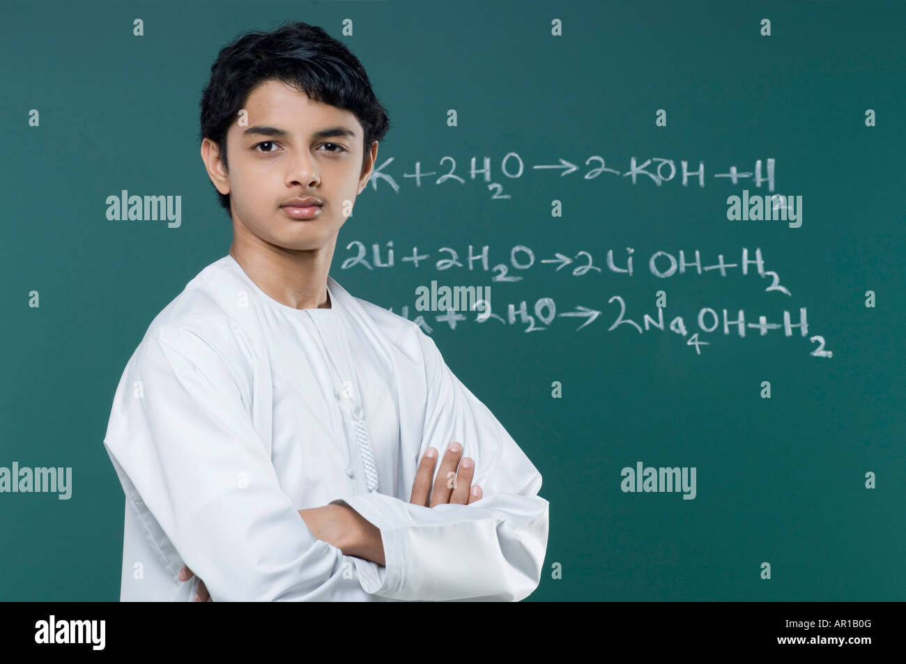 Teenage boy standing with folded hands by blackboard, portrait Stock ...