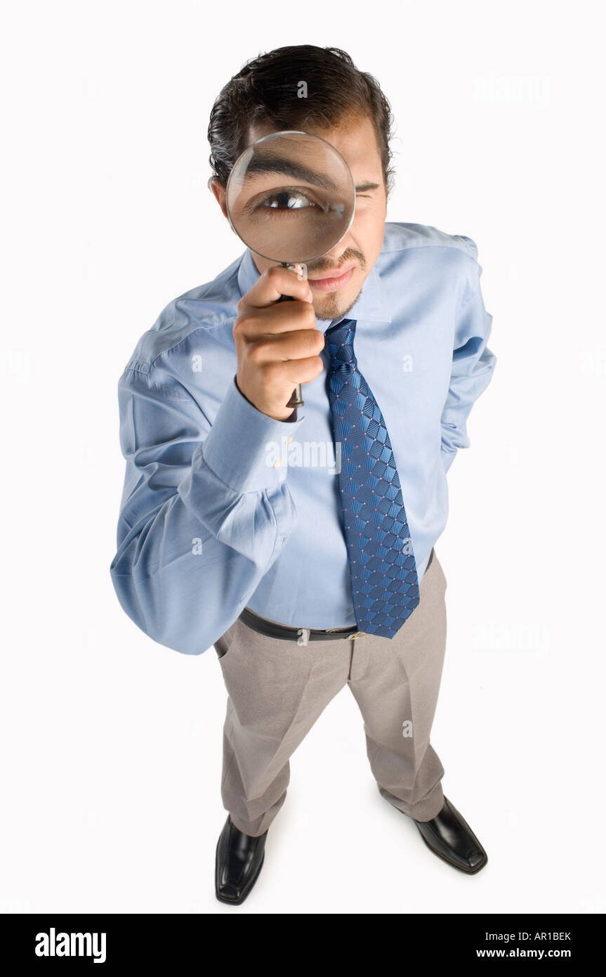 Young man looking through magnifying glass, portrait, elevated view ...