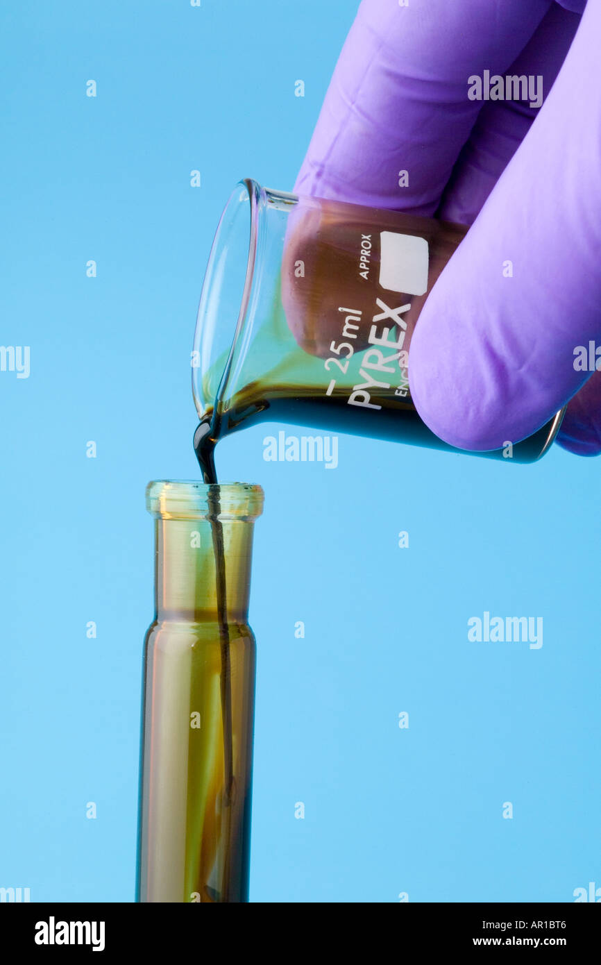Crude oil being poured from a glass beaker Stock Photo - Alamy