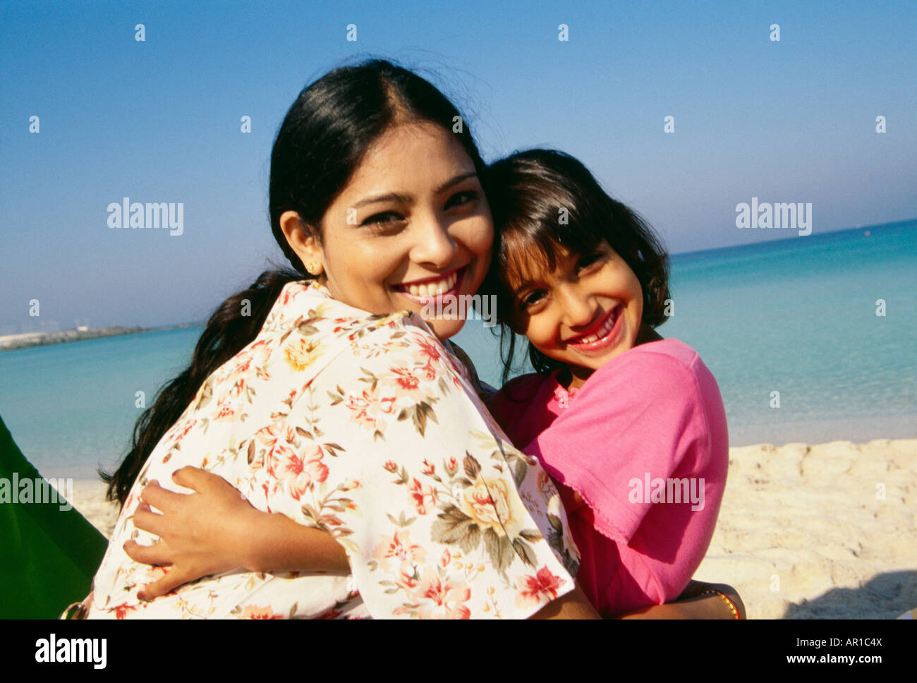 Mother and daughter hug each other as they smile at the camera Stock ...