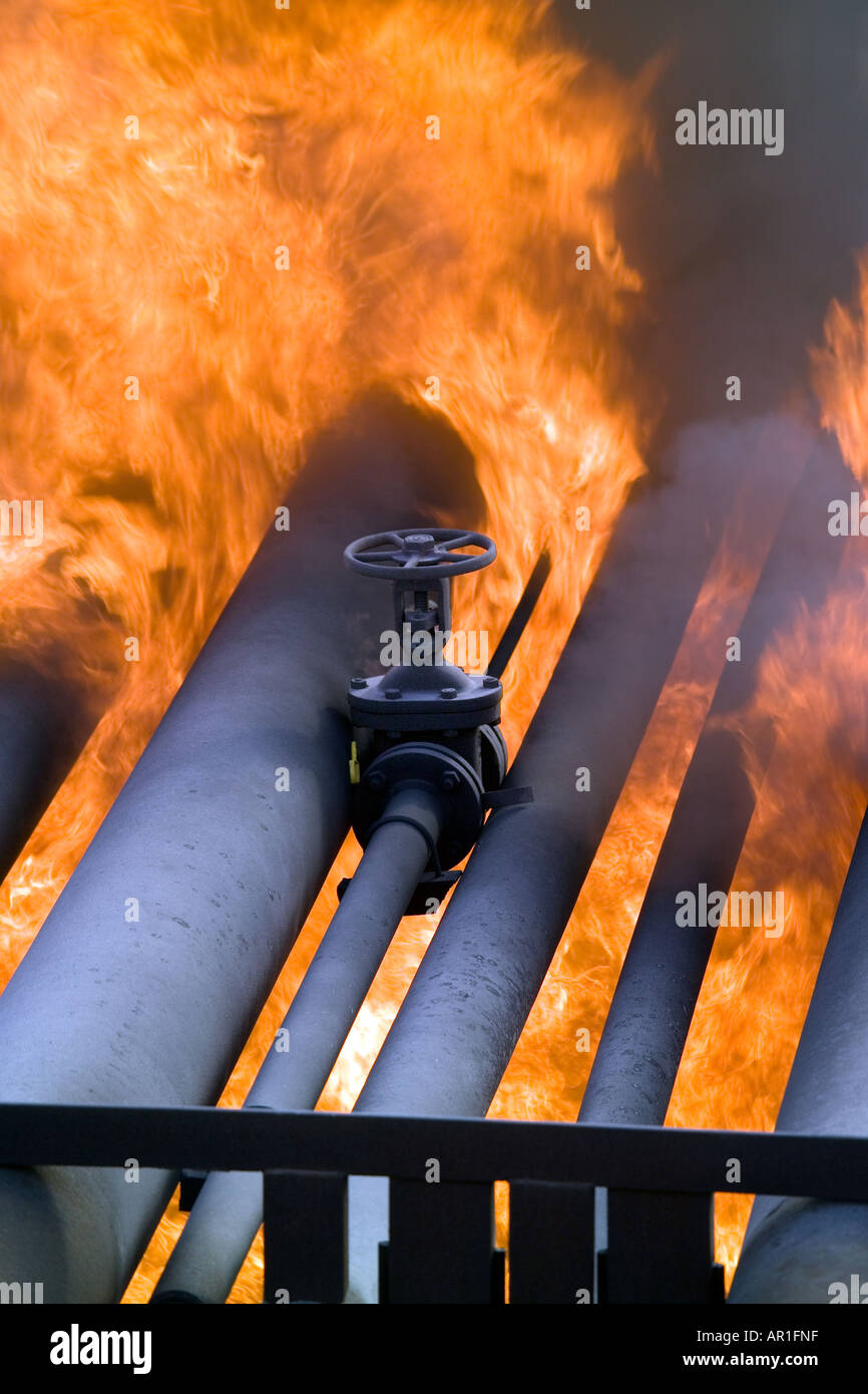 Liquid on fire below industrial pipe rack and valve Stock Photo - Alamy