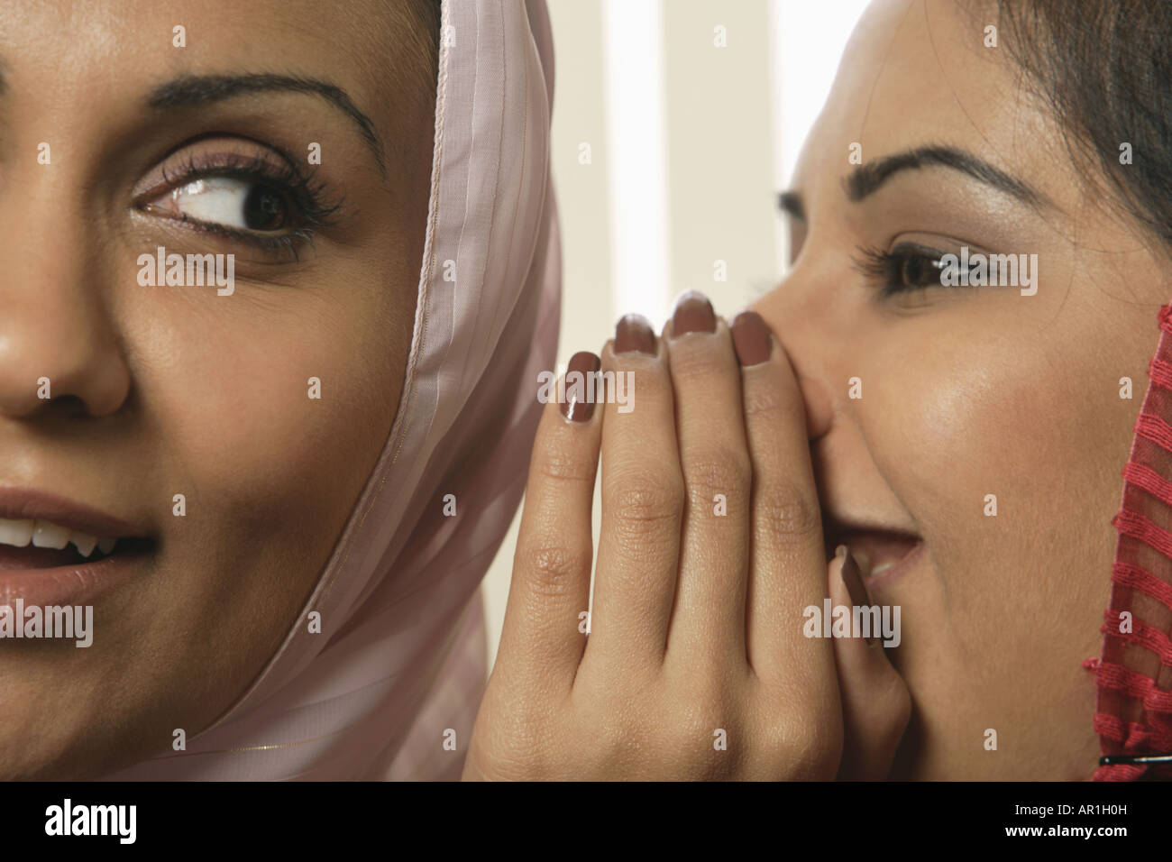 Lady whispering something in her friend Stock Photo - Alamy