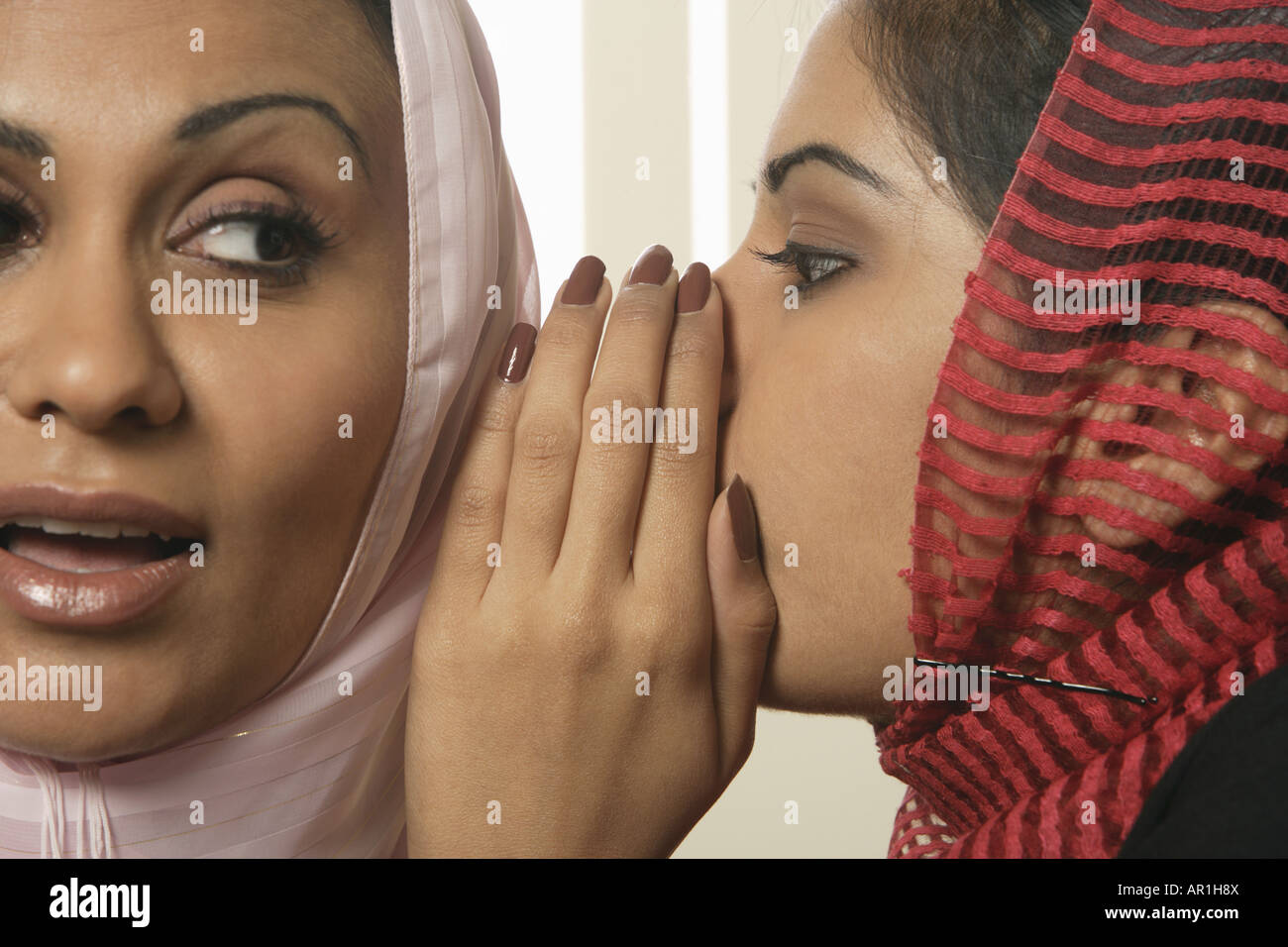 Lady whispering something in her friend Stock Photo - Alamy