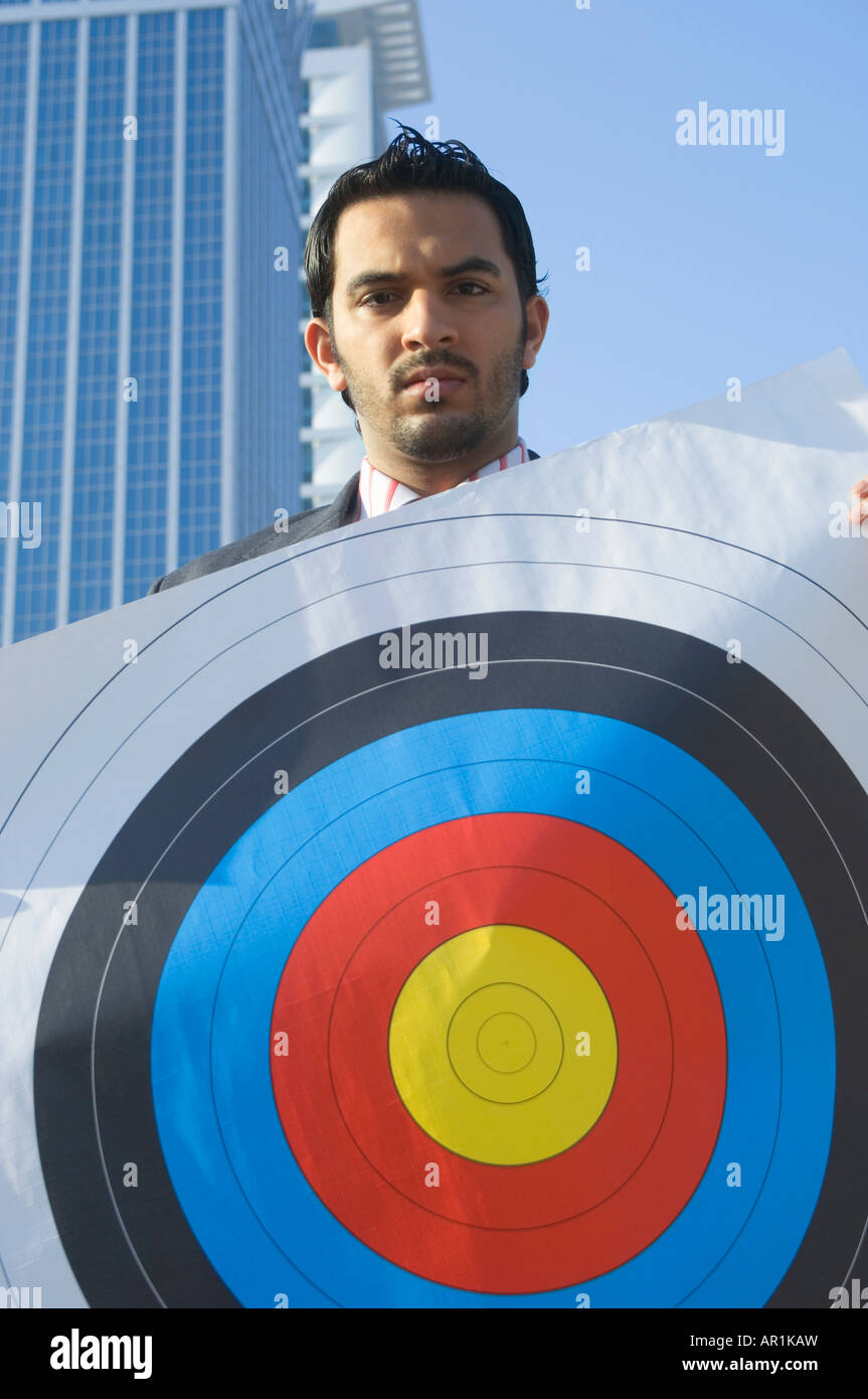 Young man holding a target board outdoors with skyscrapers in the ...