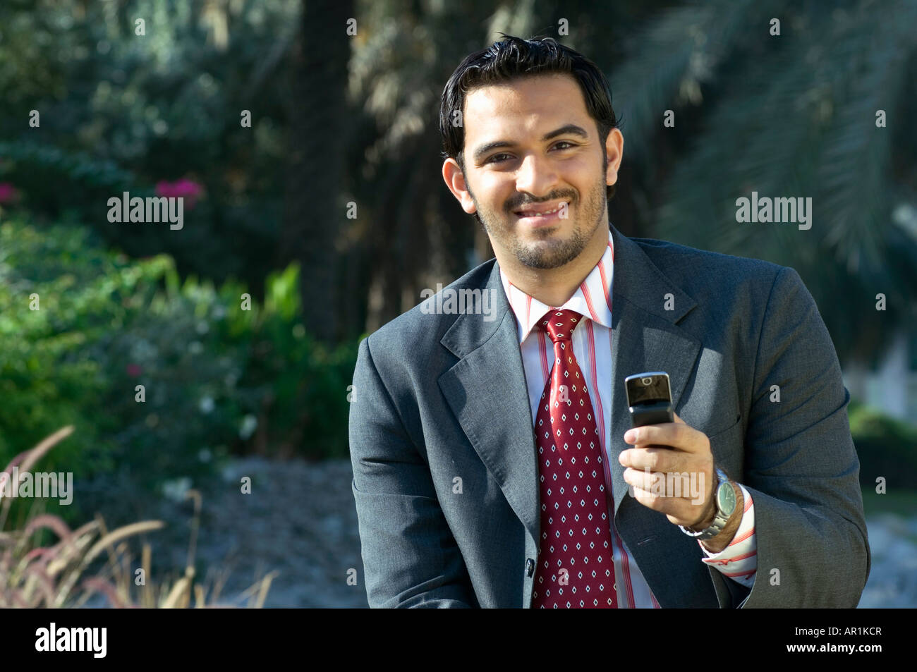 Young man holding a cell phone and smiling Stock Photo - Alamy