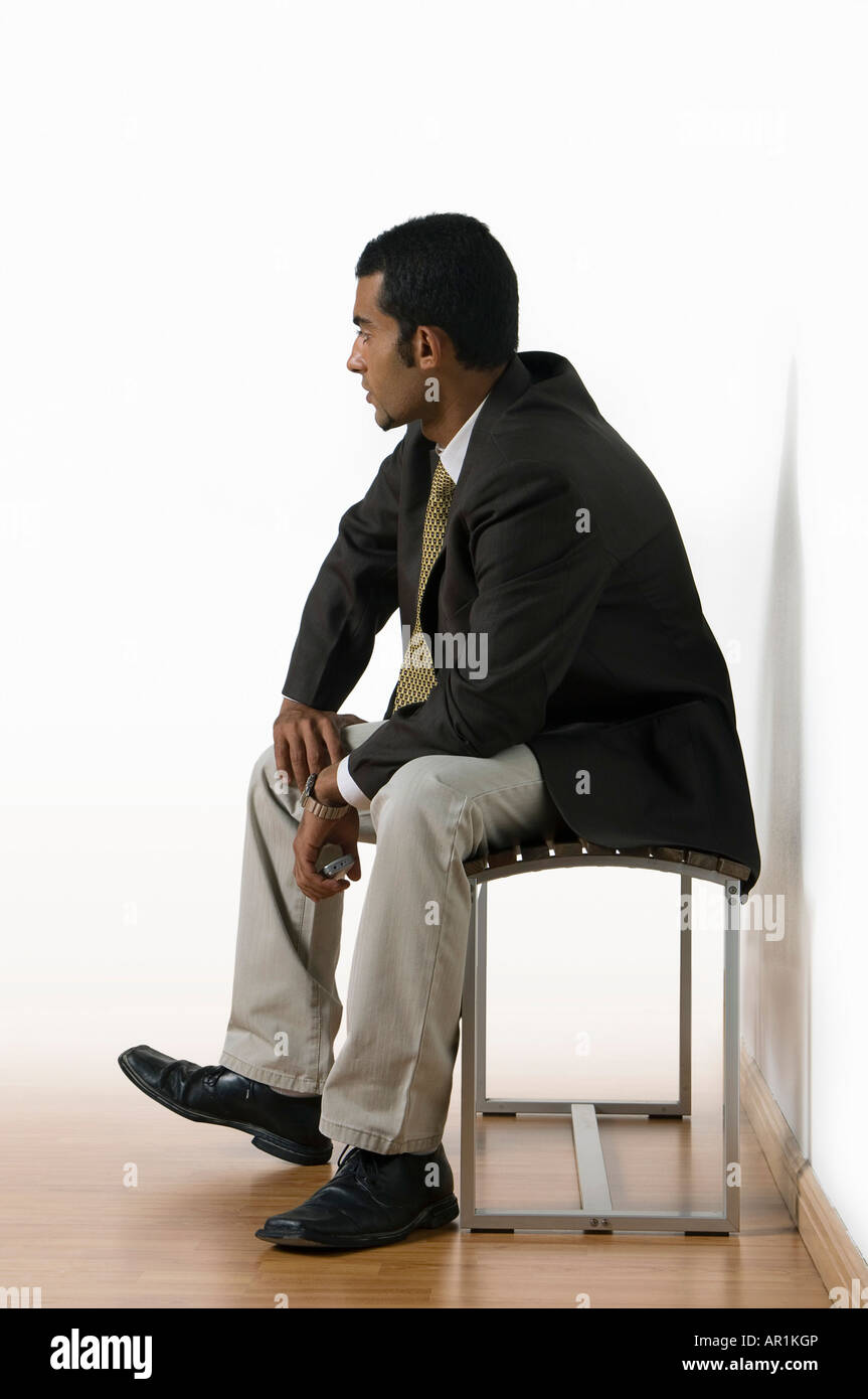 Young man sitting waiting Stock Photo - Alamy