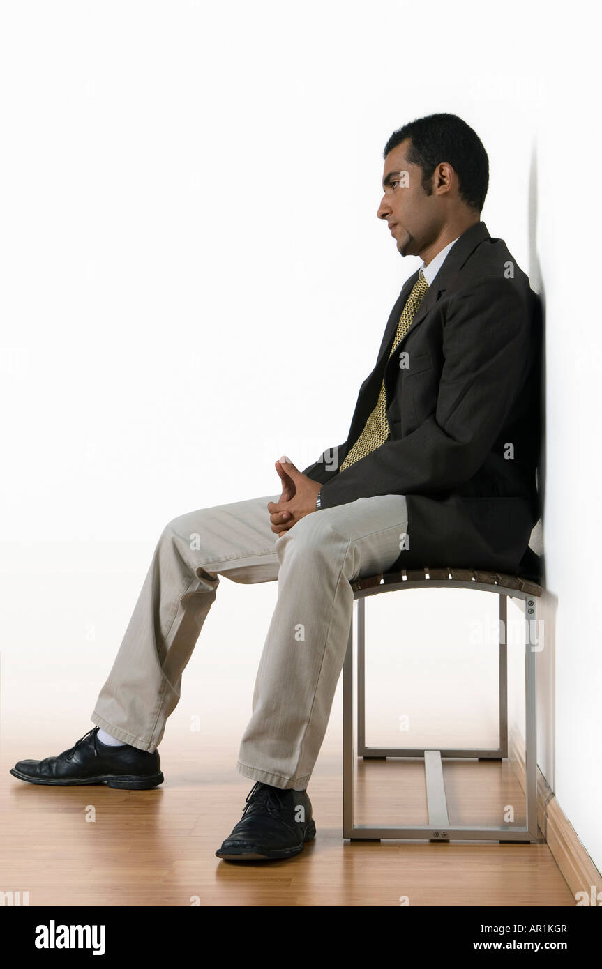 Young man sitting waiting Stock Photo - Alamy