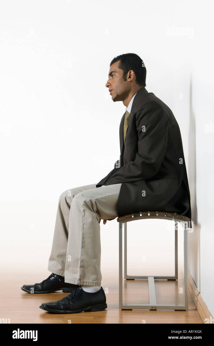 Young man sitting waiting Stock Photo - Alamy