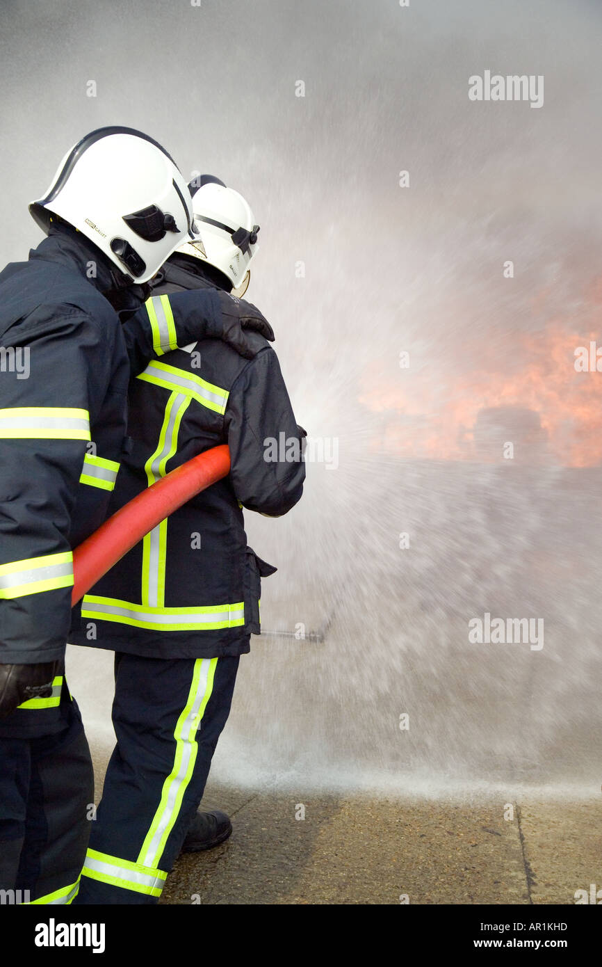 Firemen advancing fire behind water hose shield protection brave hi-res ...