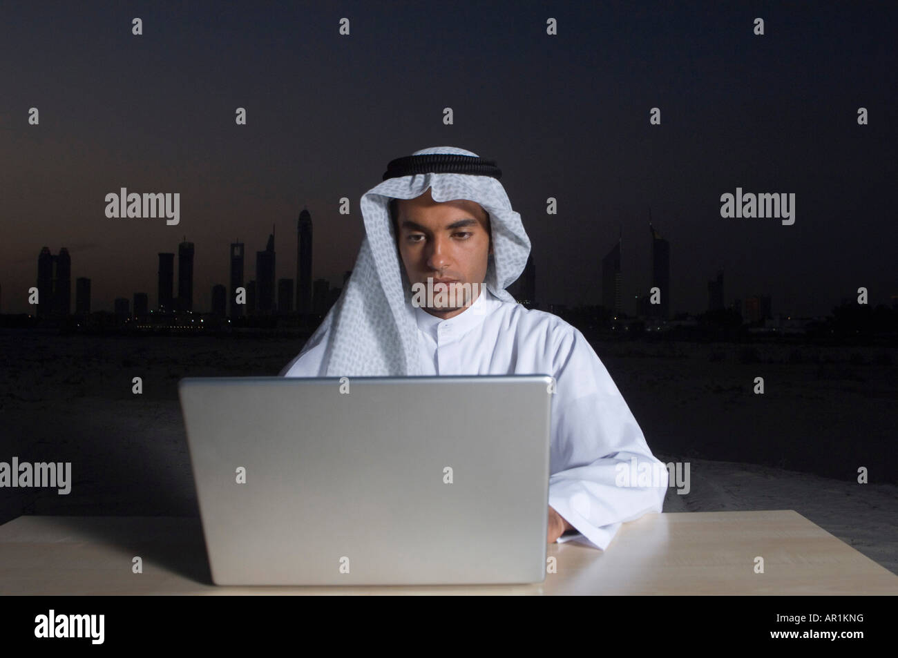 Young Arab man sitting at a desk - office with Dubai City in the ...