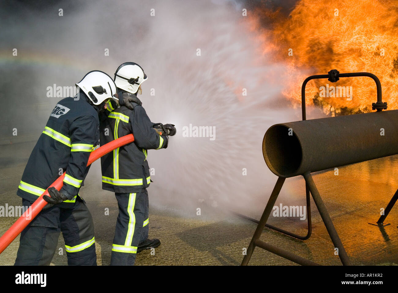 Firemen advancing fire behind water hose shield protection Stock Photo ...