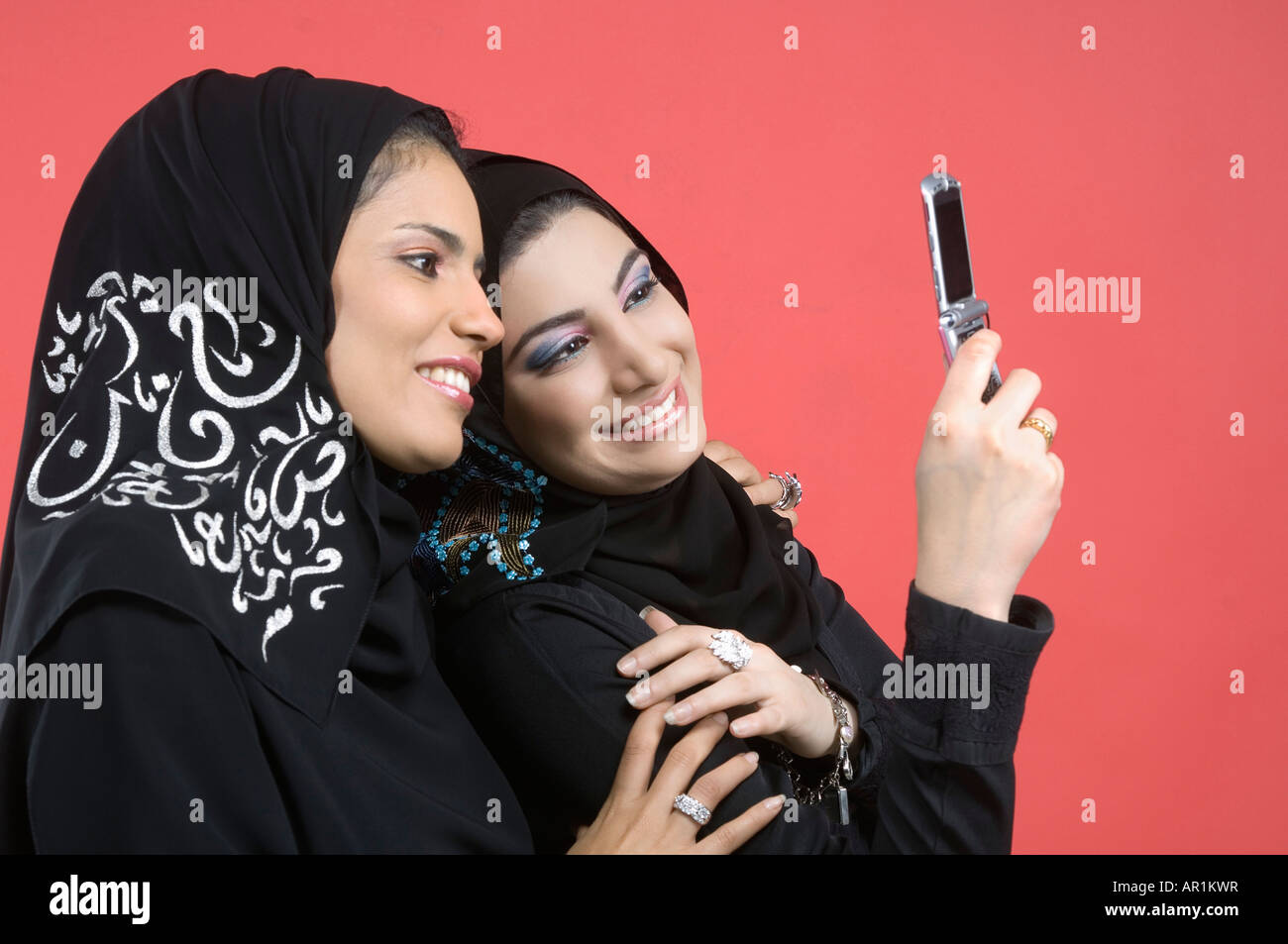 Two Arab Ladies standing cheek to cheek with cell phone Stock Photo - Alamy