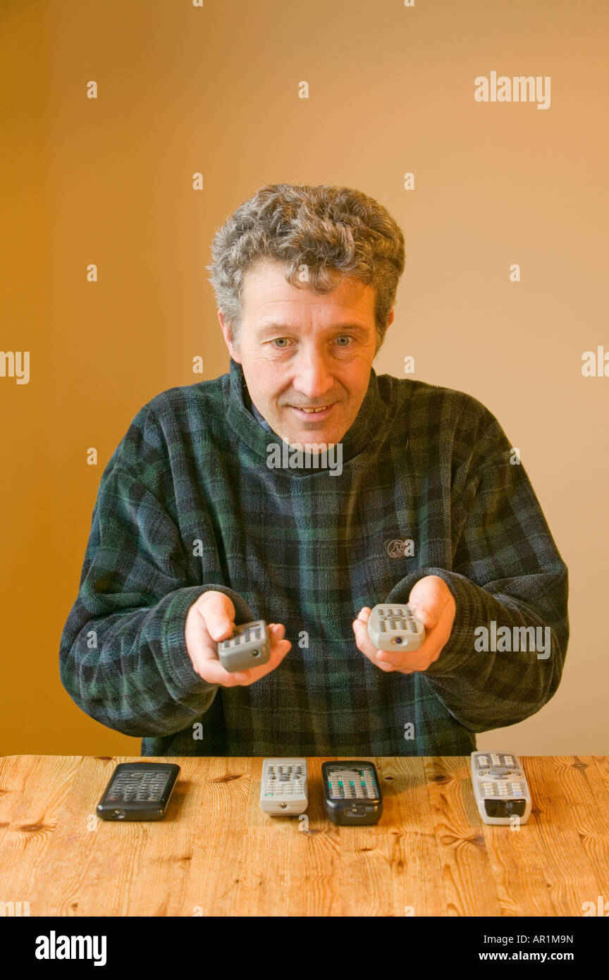 A man confused over which remote control to pick Stock Photo - Alamy