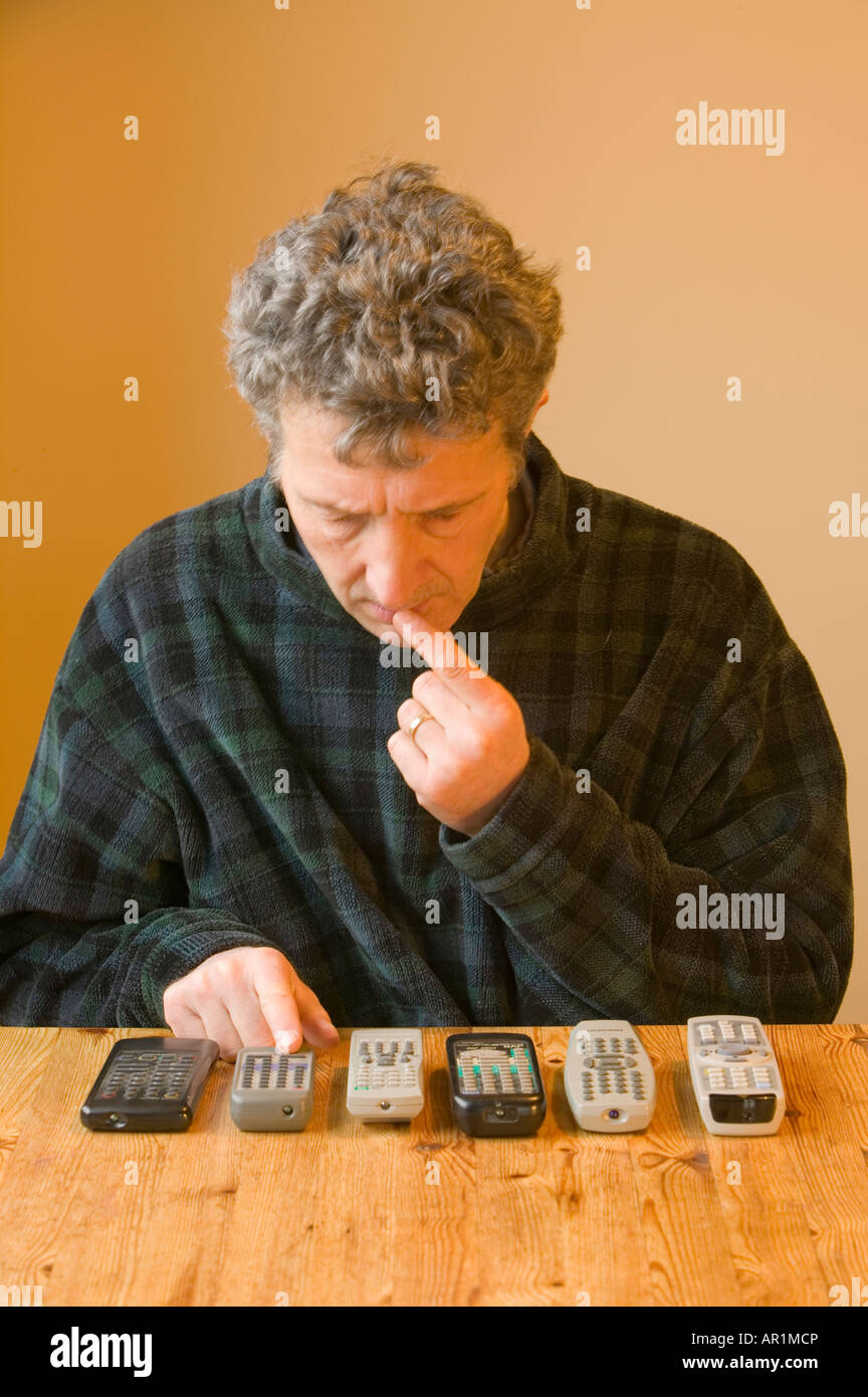 A man confused over which remote control to pick Stock Photo - Alamy