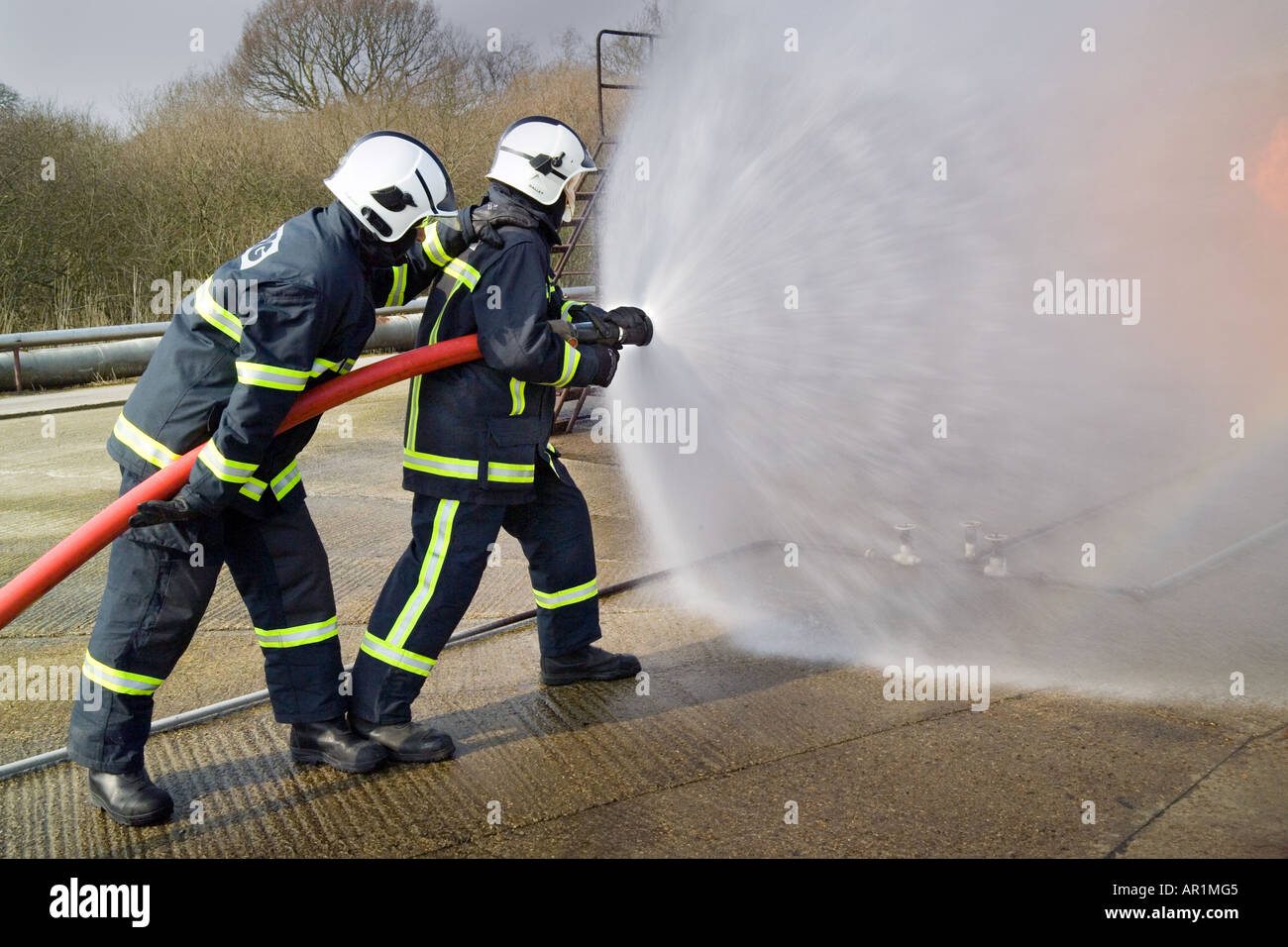 Firemen advancing fire behind water hose shield protection Stock Photo ...
