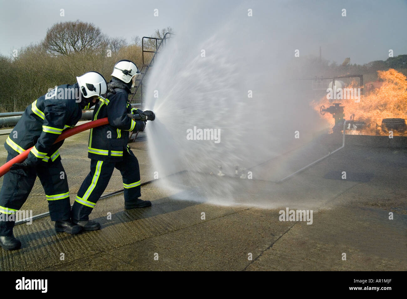 Firemen advancing fire behind water hose shield protection Stock Photo ...