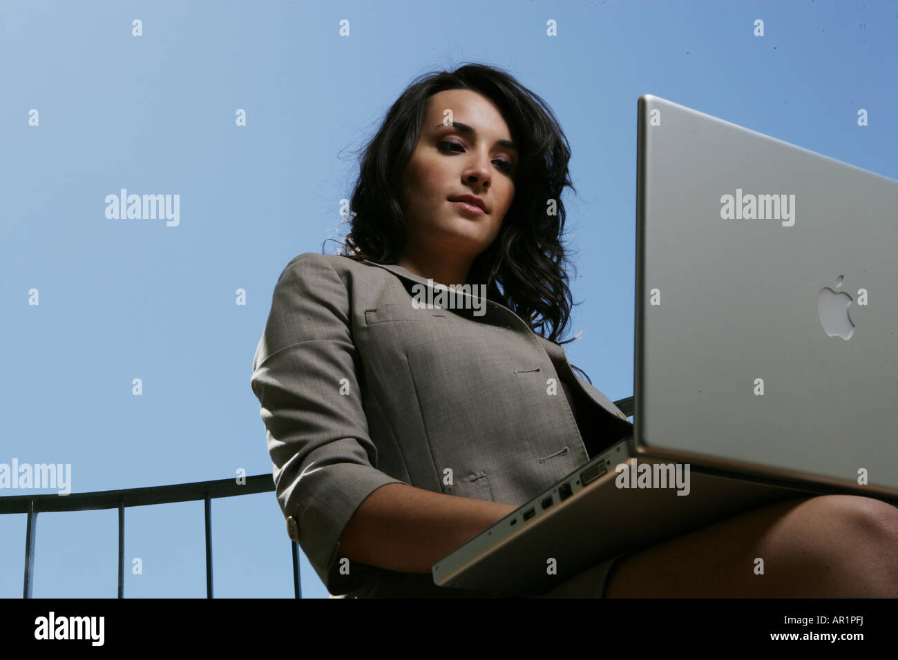 Woman holding a laptop, looking down at camera Stock Photo - Alamy