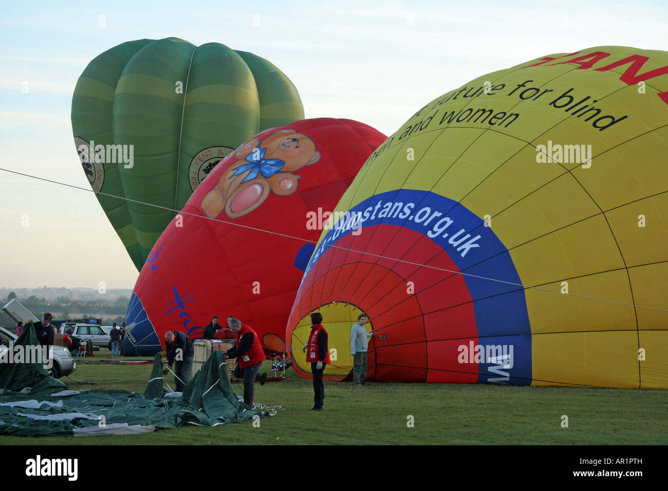 three hot air balloons being prepared for take off, half inflated ...