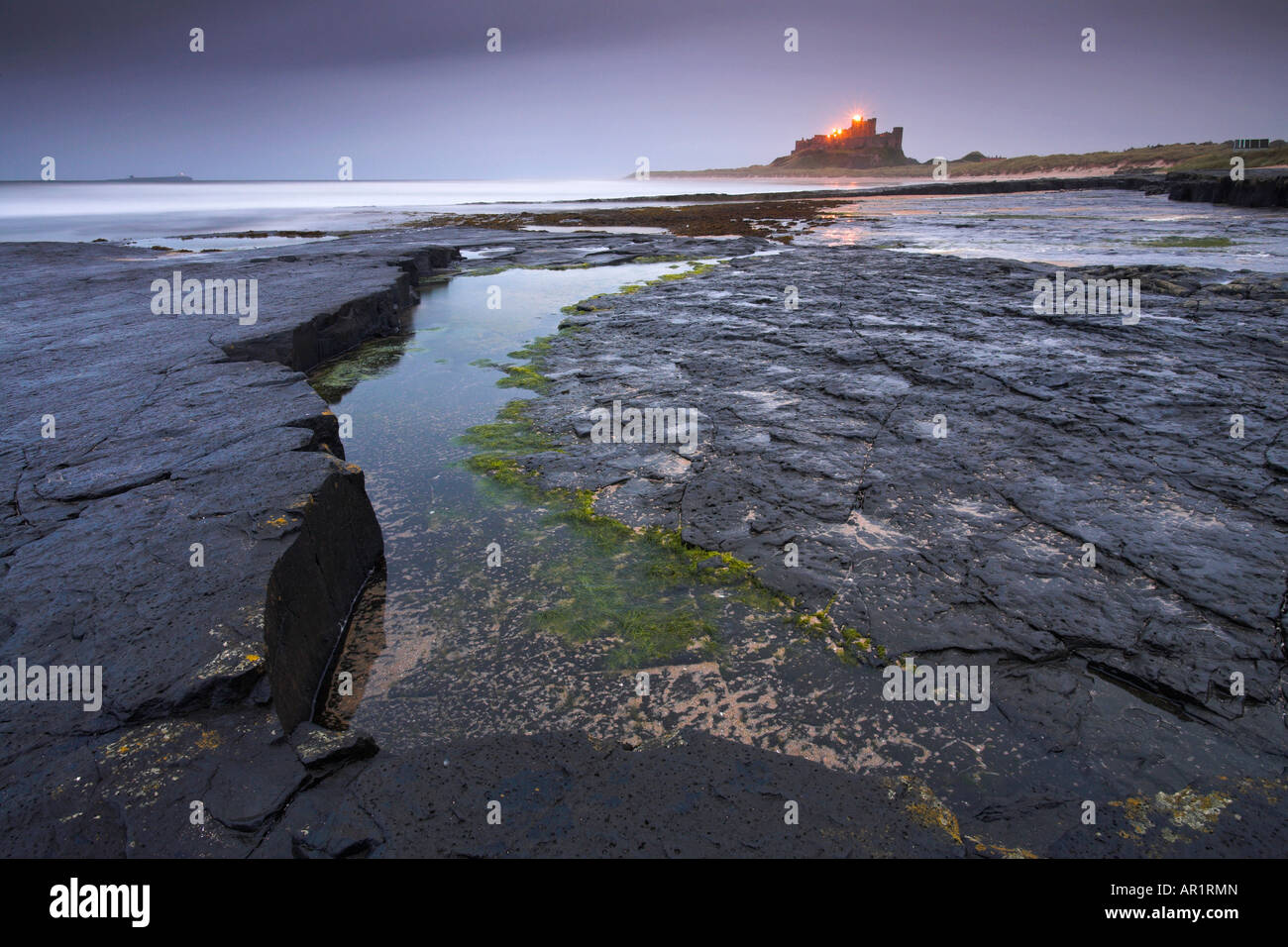 Volcanic basalt rocks at Bamburgh Castle, Northumberland Stock Photo ...