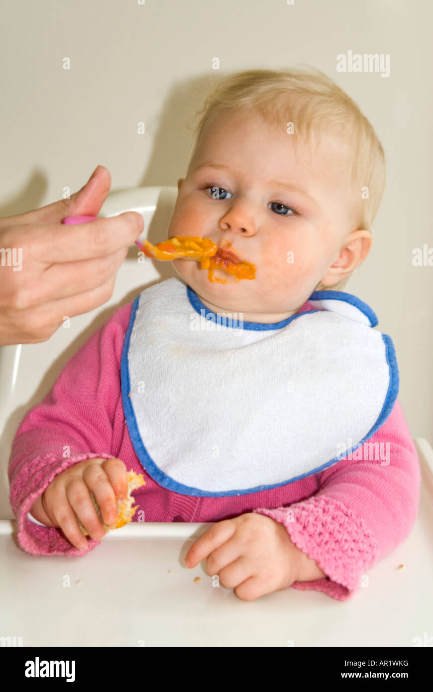 Vertical close up of a pretty Caucasian baby girl sitting at her high ...