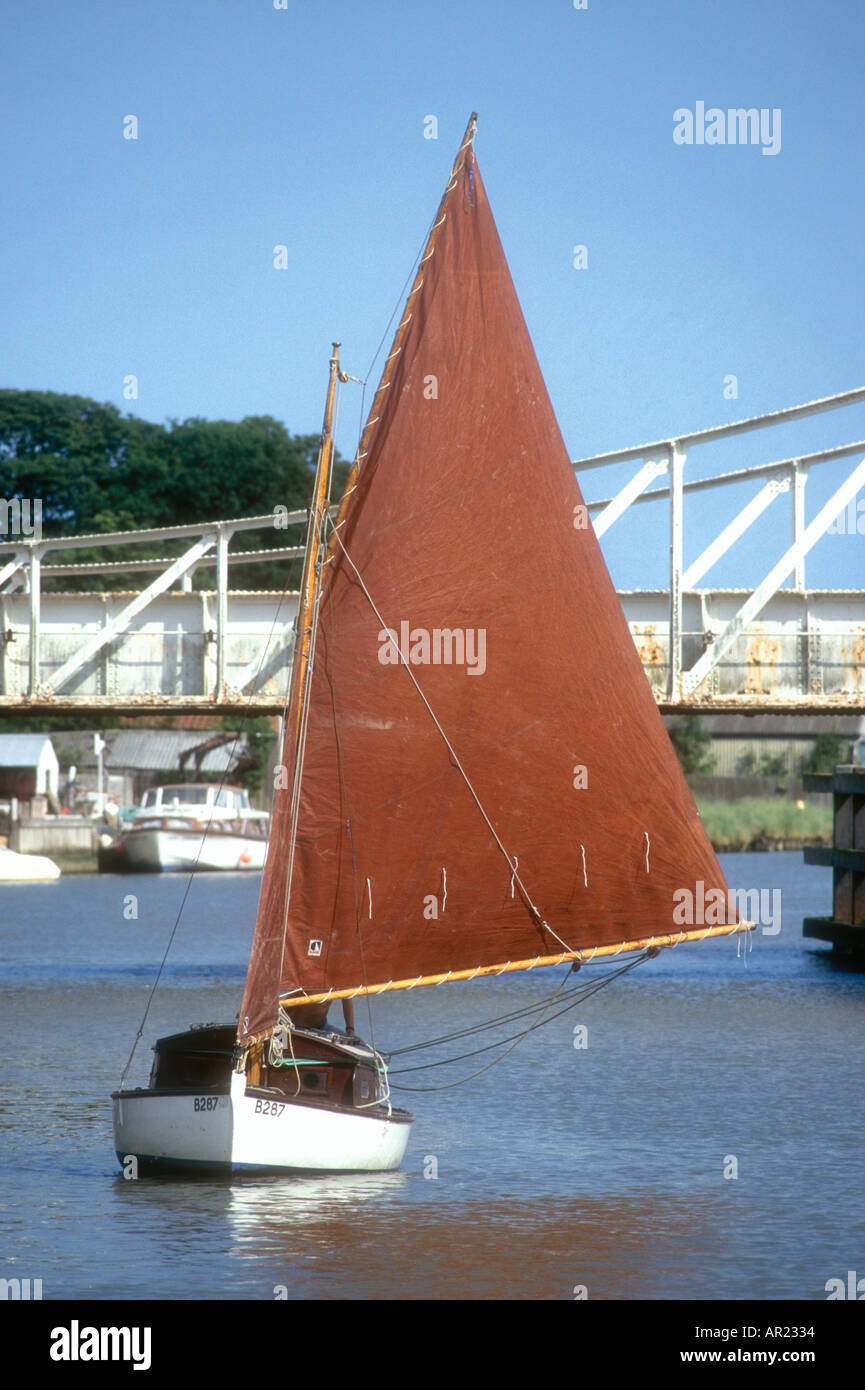 A yacht cruising the River Yare at Reedham in the Norfolk Broads ...