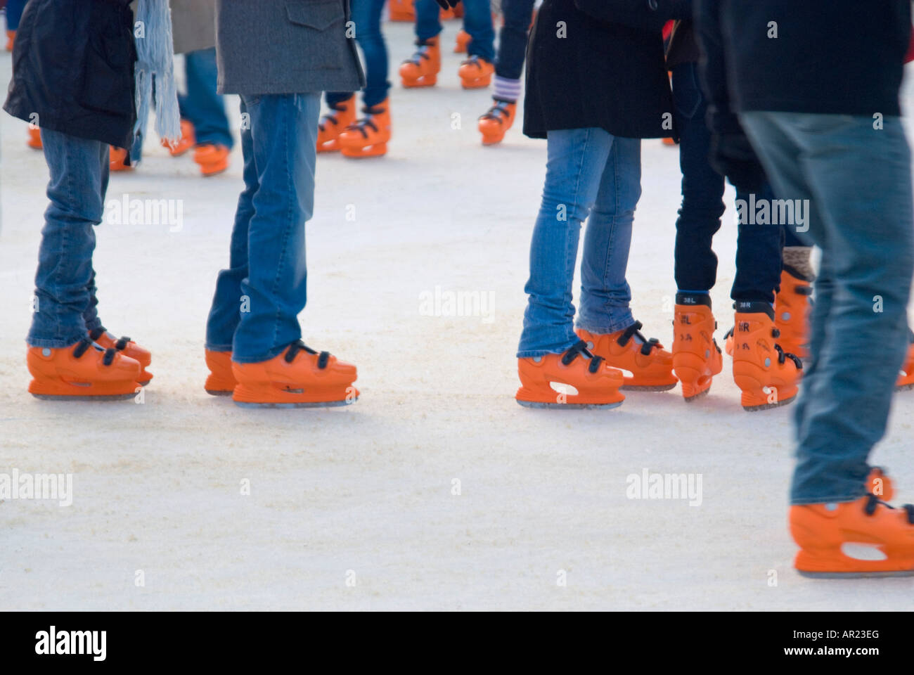 Horizontal close up of bright orange hired ice skates on a busy open ...