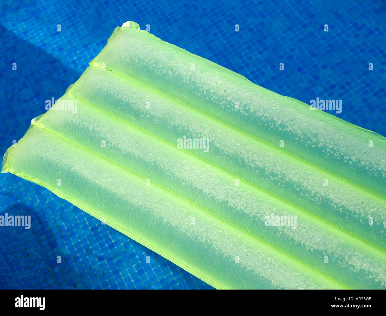 Yellow green inflatable lilo in blue tiled swimming pool Stock Photo ...