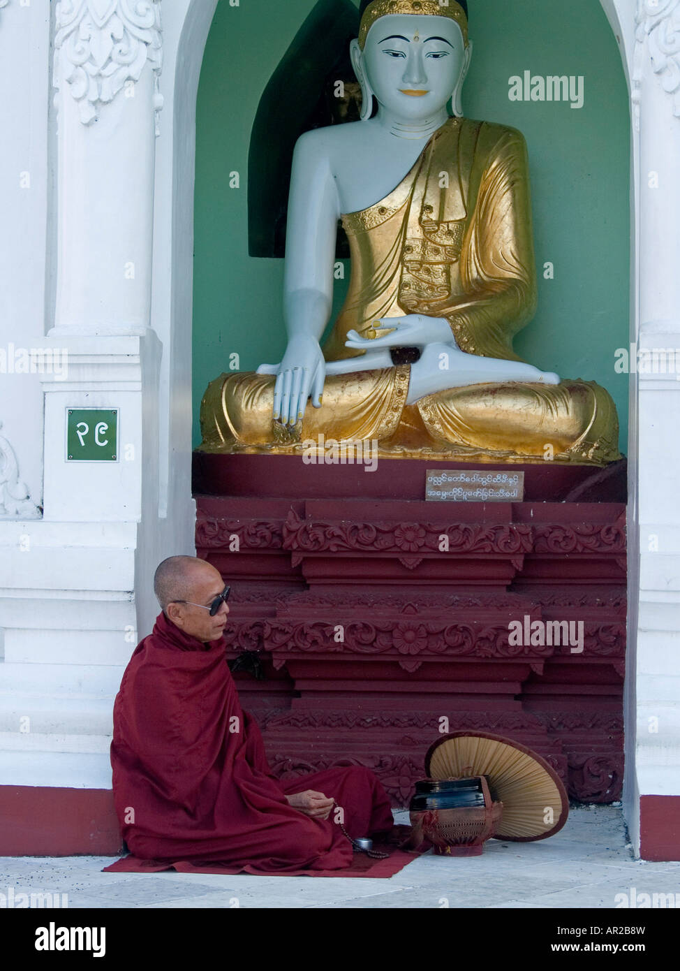 a monk sits meditating under a Buddha statue at Shwedagon Paya Burma s ...