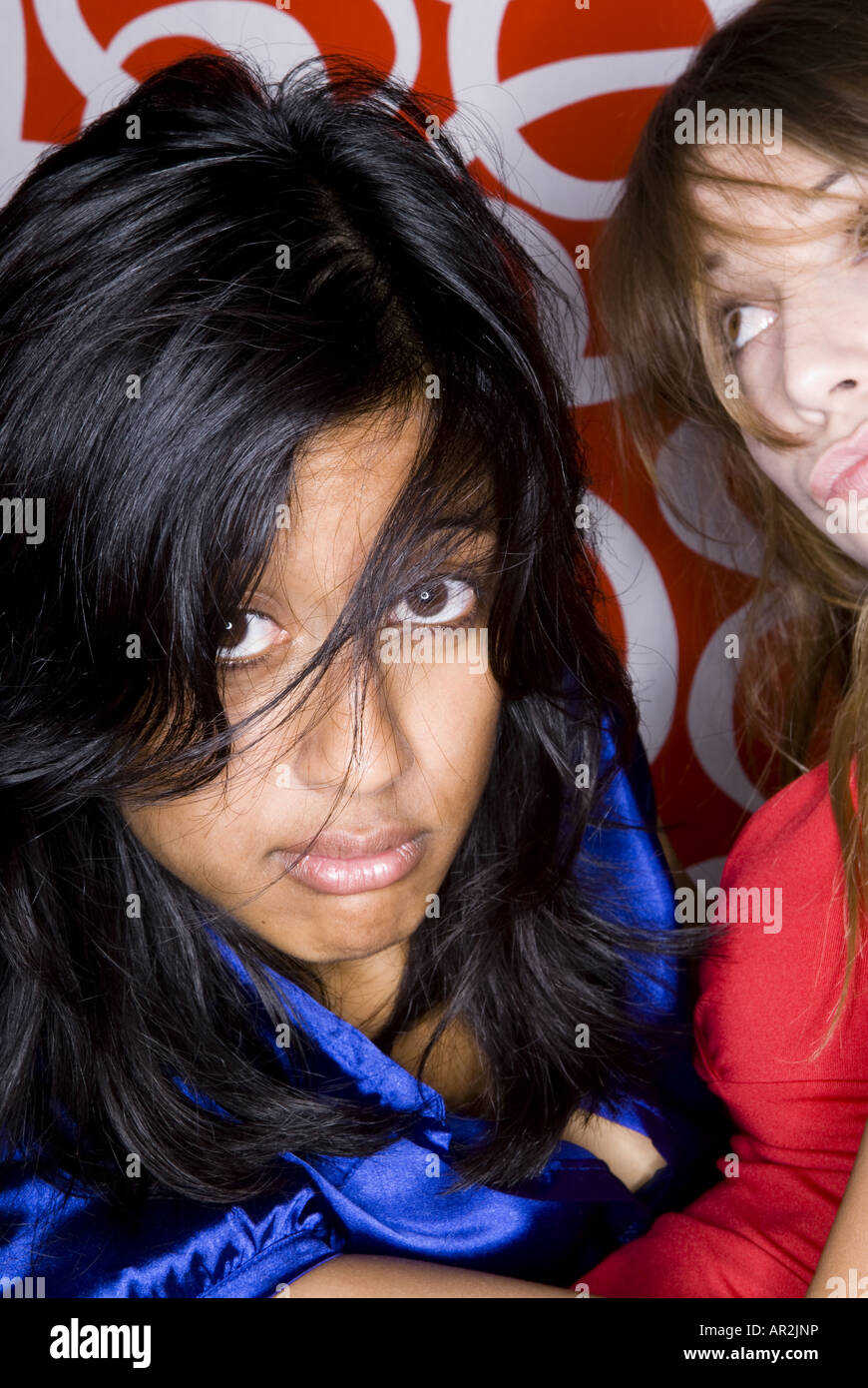 two bored girlfriends, a light-skinned and a dark-skinned woman sitting ...