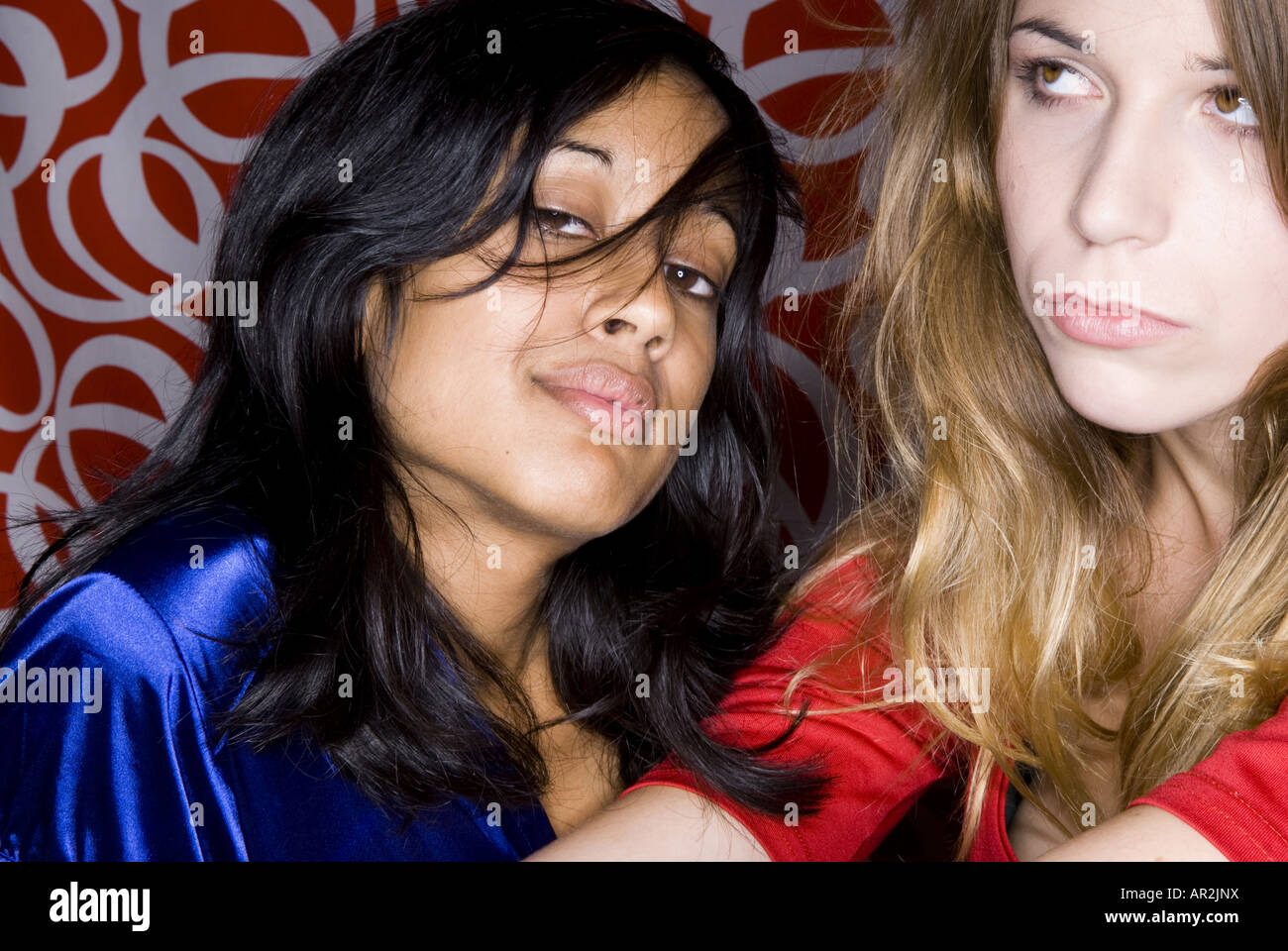 two bored girlfriends, a light-skinned and a dark-skinned woman sitting ...