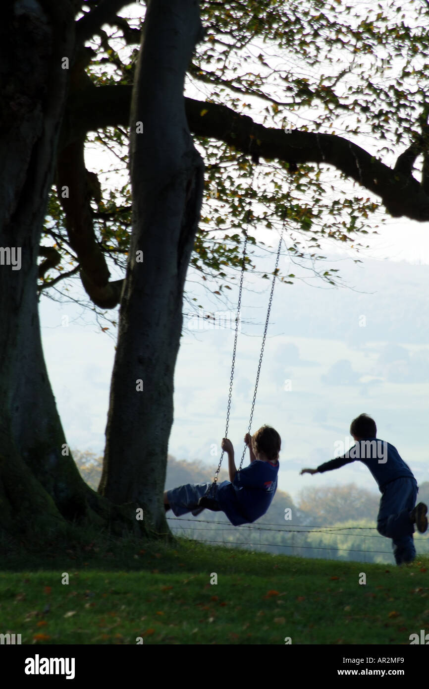 children playing on a swing hung from a tree branch Stock Photo - Alamy