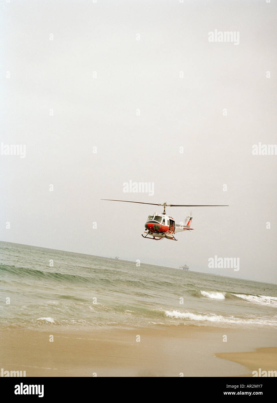 Rescue helicopter flying over beach Stock Photo - Alamy
