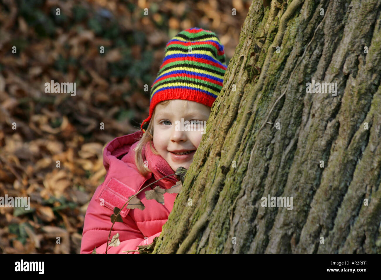 Happy children hiding behind tree hi-res stock photography and images ...
