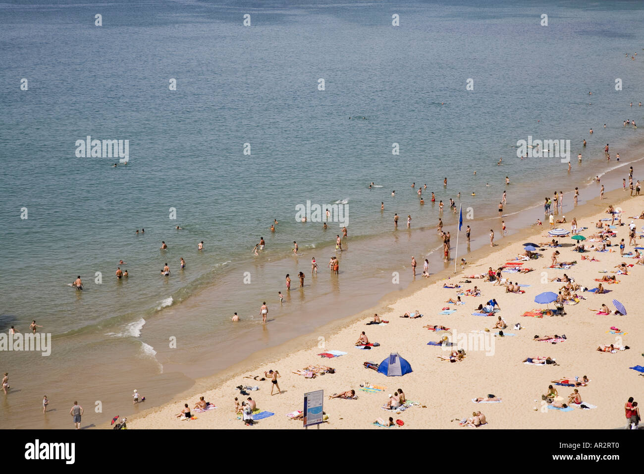 People swimming in sea and sunbathing on beach Stock Photo - Alamy