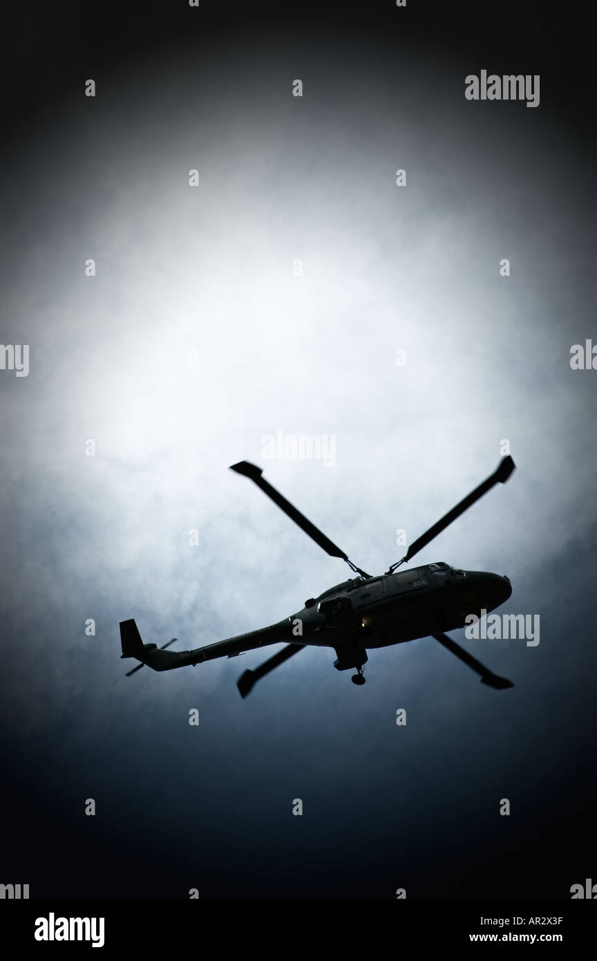 Silhouette of an in flight RAF rescue helicopter against a bright sky ...