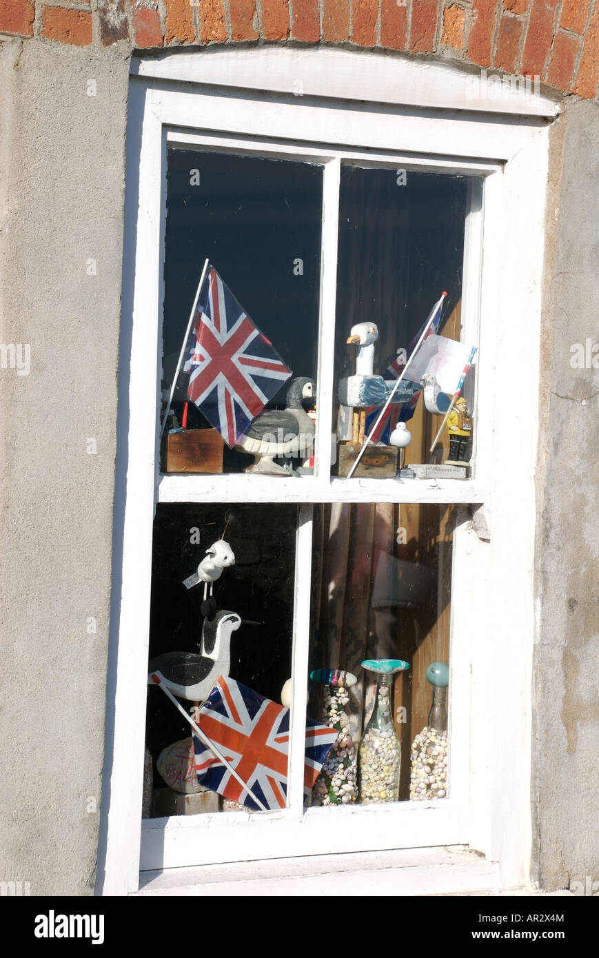 Union jack flags, toy birds and seaside memorabilia in a cottage window ...