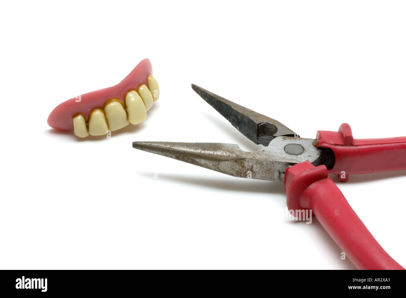 Comedy false teeth and a set of pincers cut out against a white ...