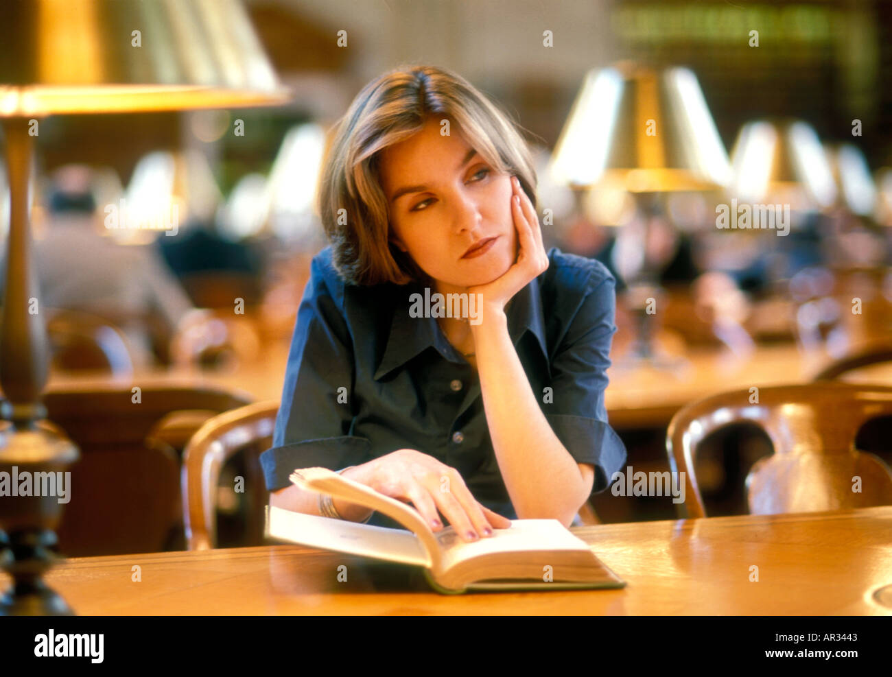 Public Library Woman with book thinking Stock Photo - Alamy