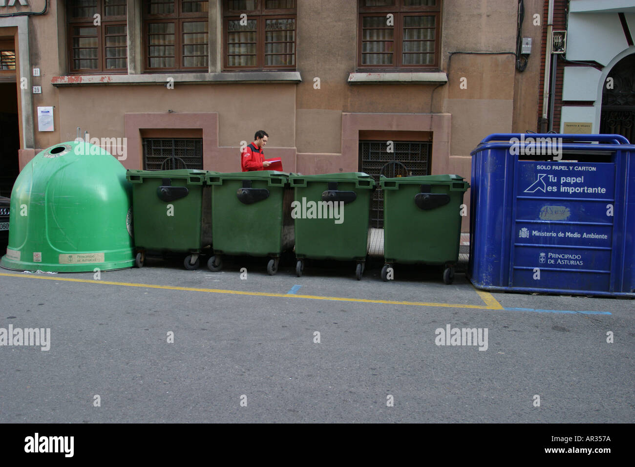 Four garbage containers and two recycling containers on the street ...