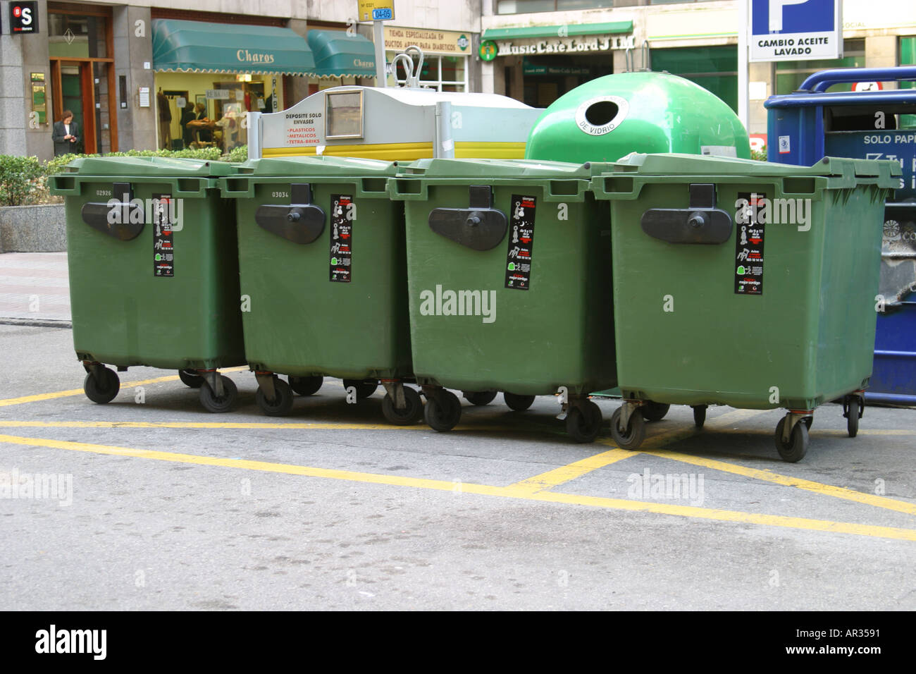 Four green garbage containers on the street with glass recycling ...