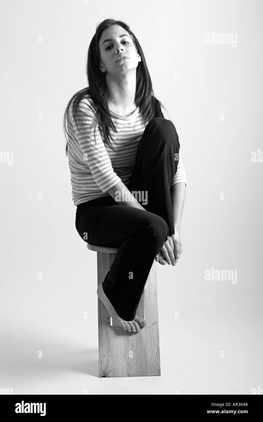 Young black haired barefoot woman with head tossed back sitting on a ...