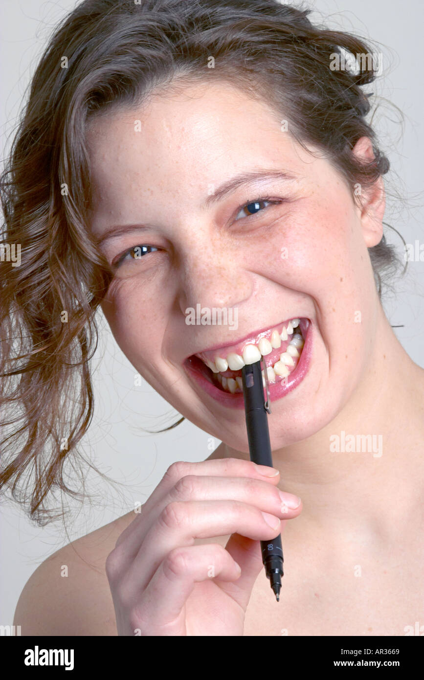 Headshot of young smiling brunnette woman with tousled hair biting on a ...
