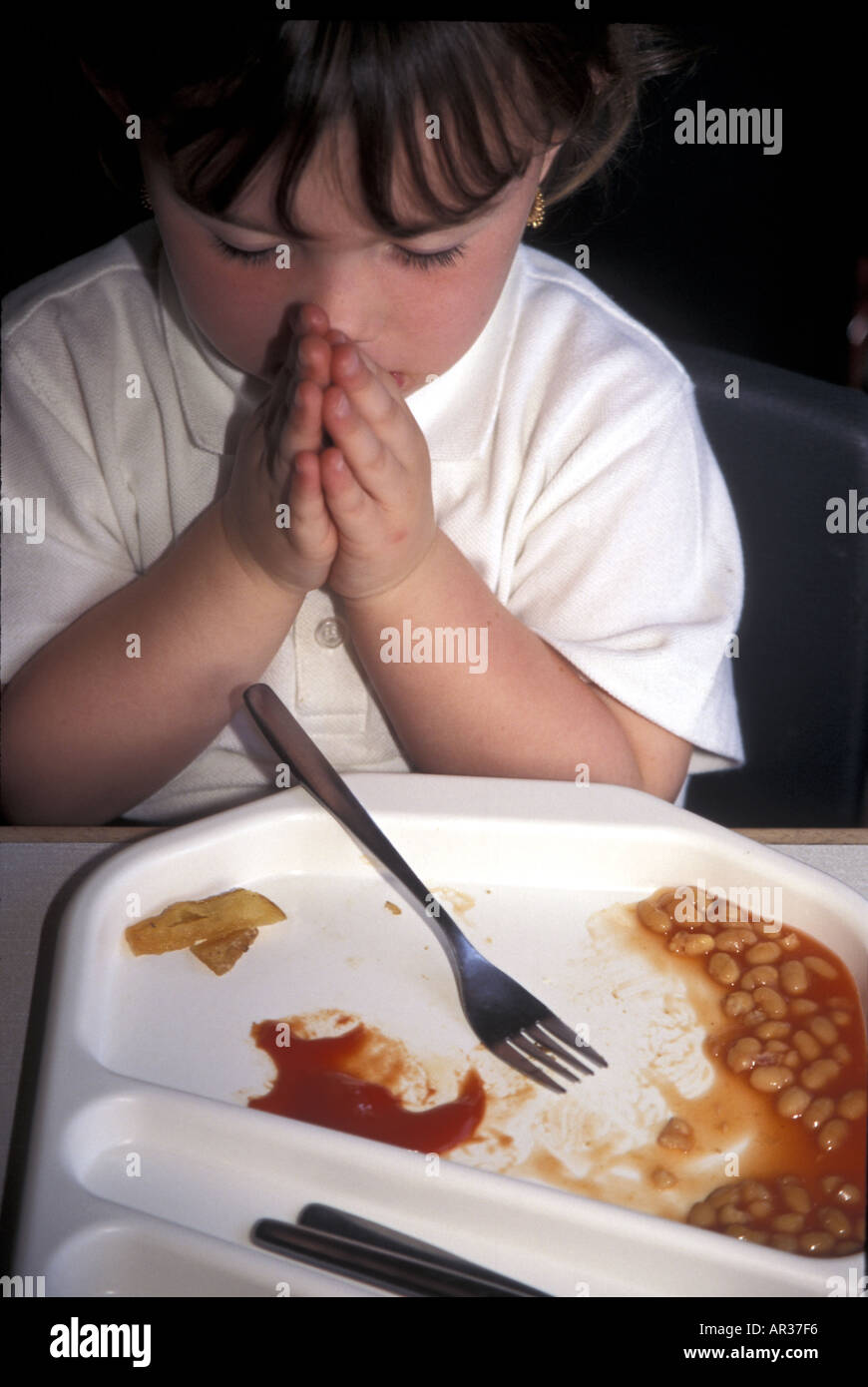 A young Christian child saying a thank you prayer at kindergarten for ...