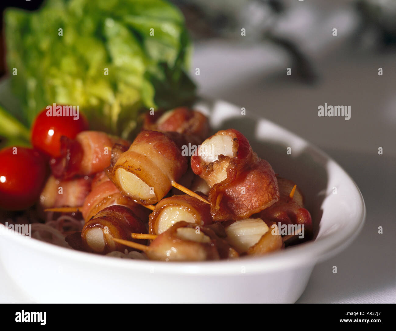 Bacon wrapped scallops in bowl with greens and cherry tomatoes Stock ...