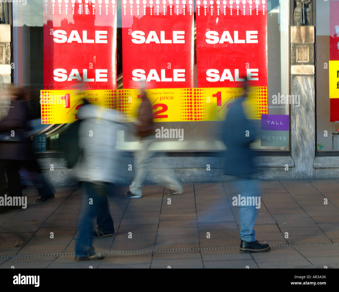 Sale signs in window of High Street store with moving shoppers in ...
