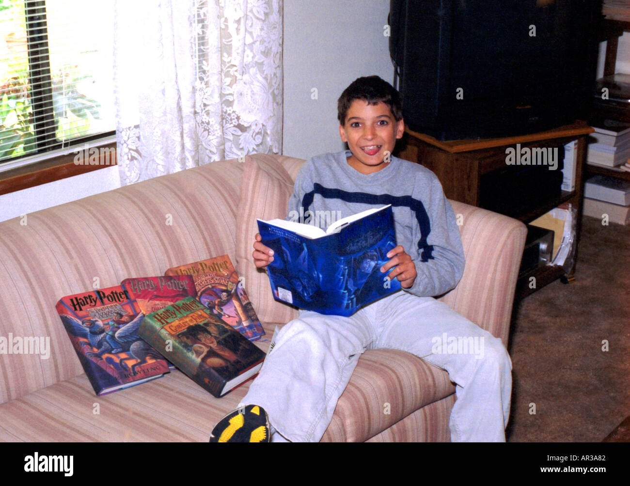 Enthusiastic young reader is enthralled with his copy of the fifth ...