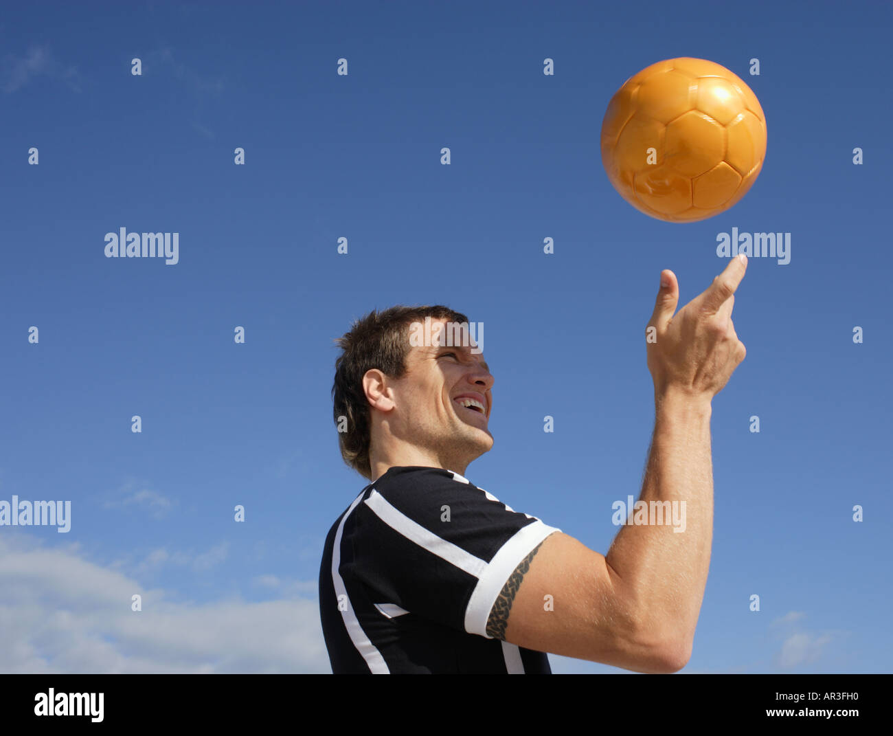 Young man wearing football shirt spinning football in air Stock Photo ...
