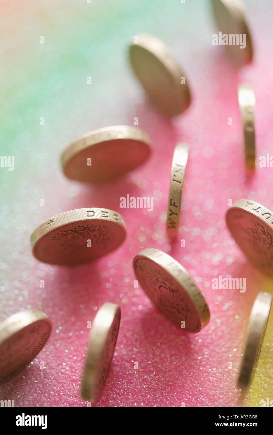 Various English one pound coins standing on their sides on a coloured ...
