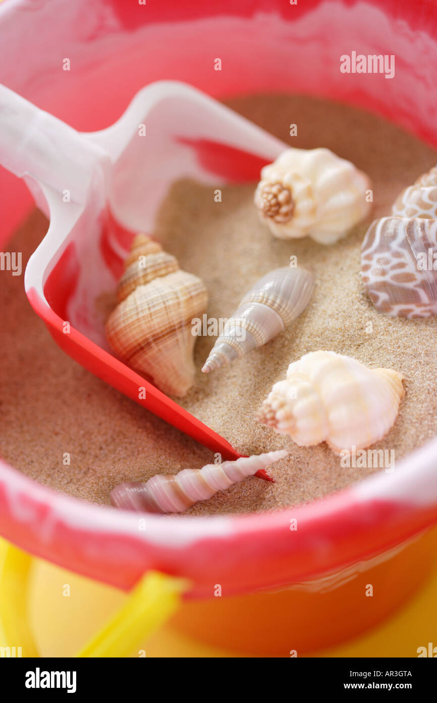 Bucket and spade filled with sand and seashells Stock Photo - Alamy